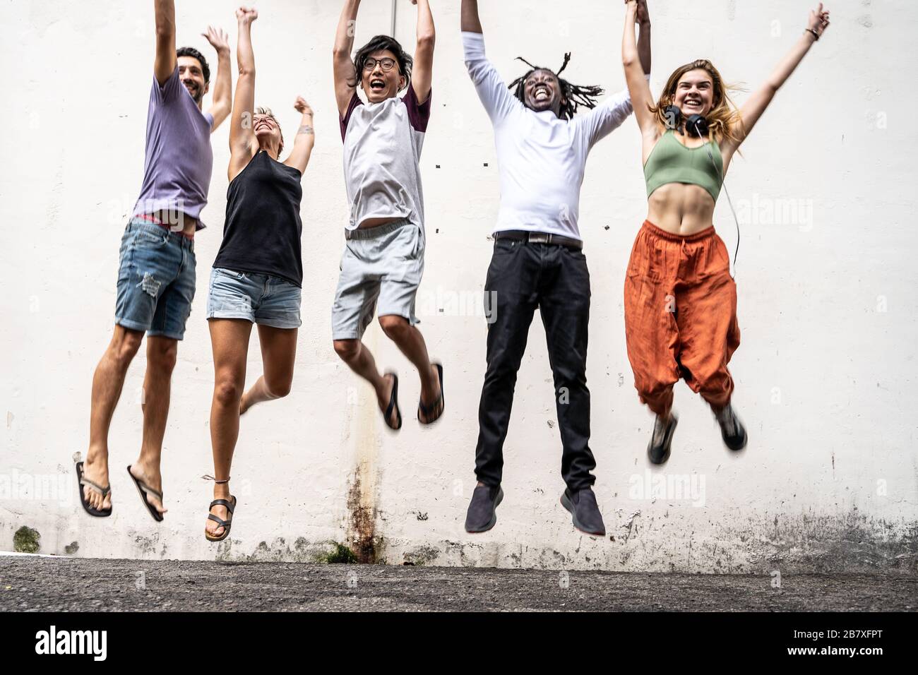 group of young people from different ethnic groups jumping next to a ...