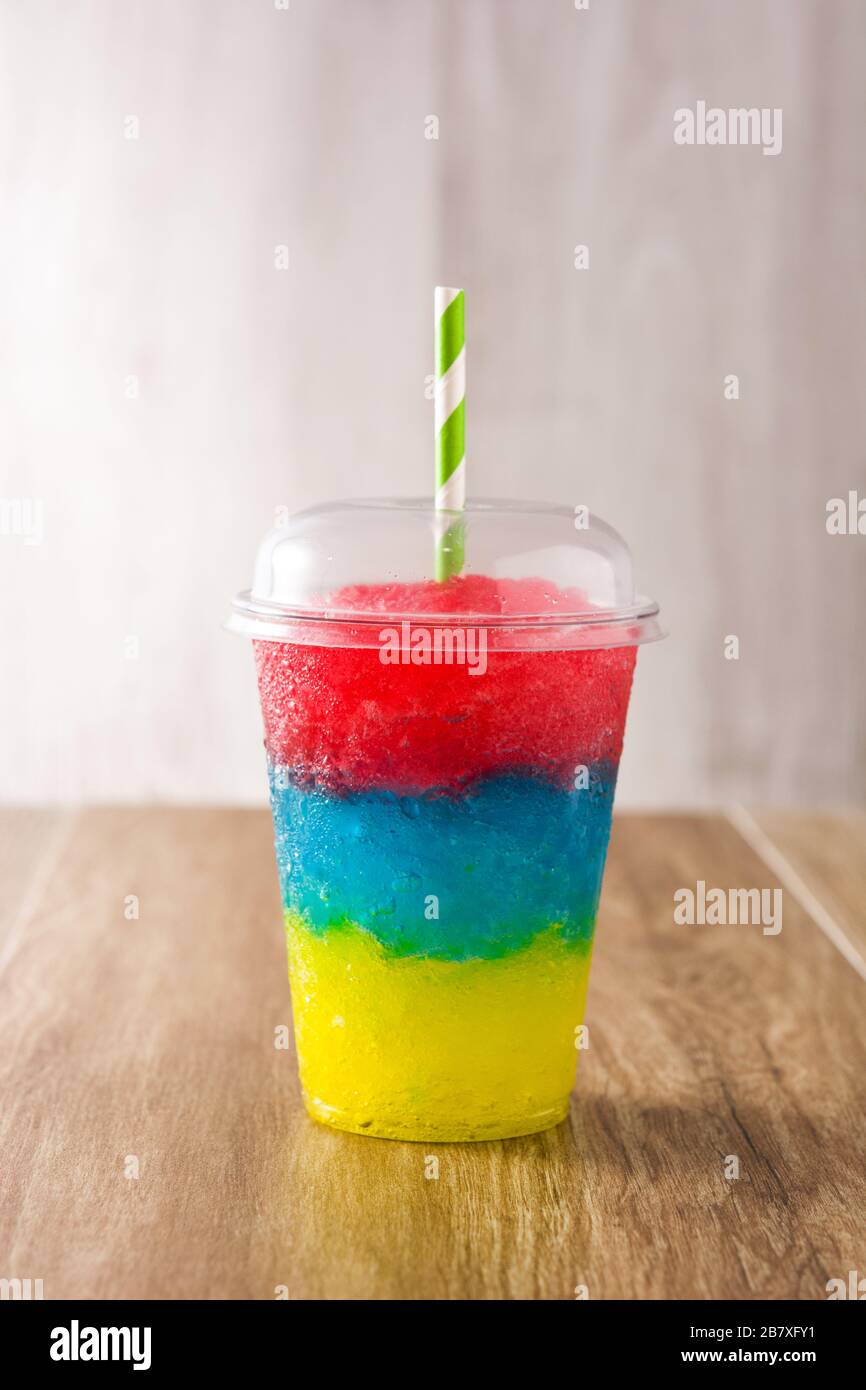 Colorful slushie of different flavors with straw in plastic cup ...