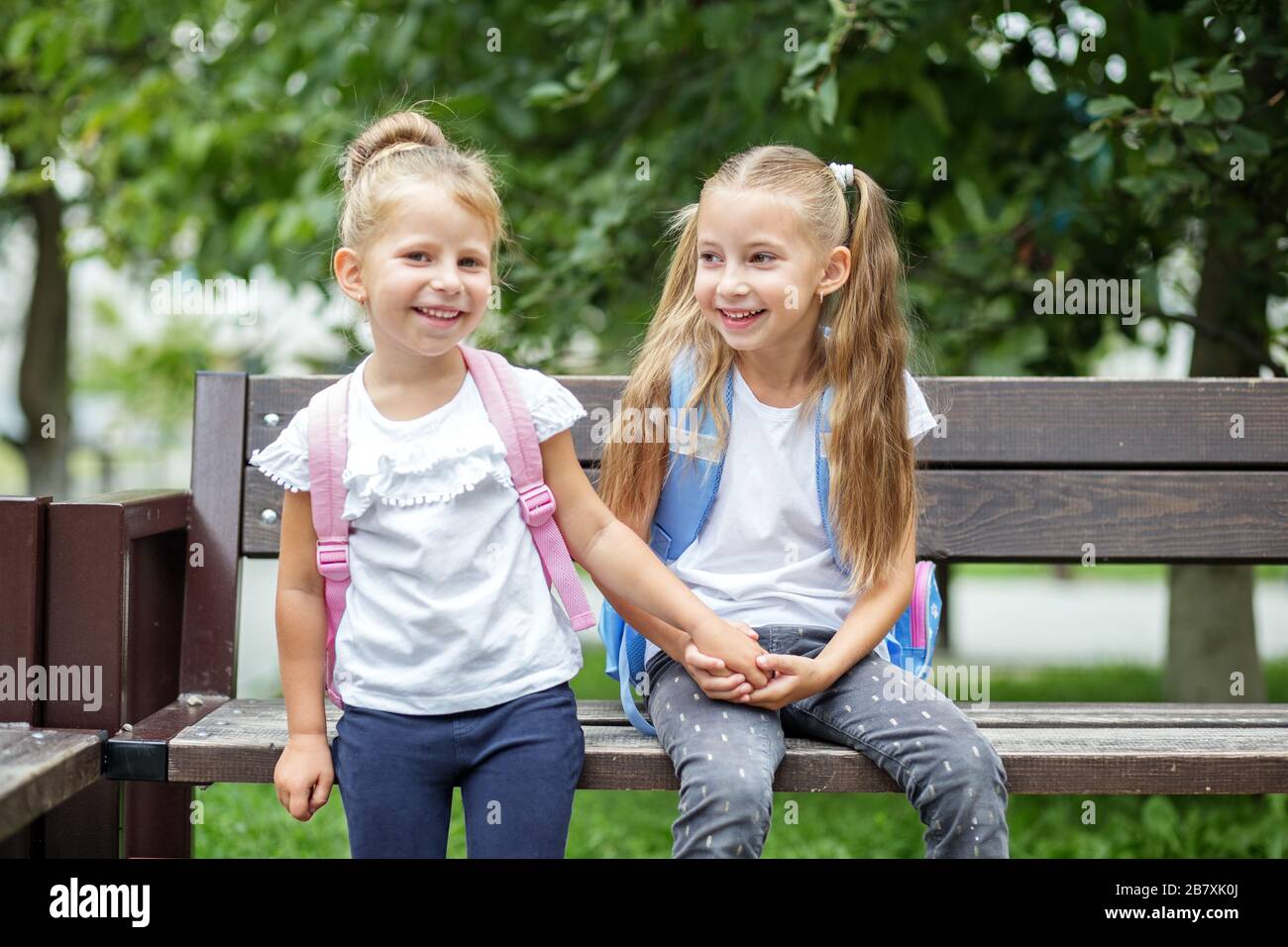 Two little children laugh and chat on a bench. The concept is back to ...