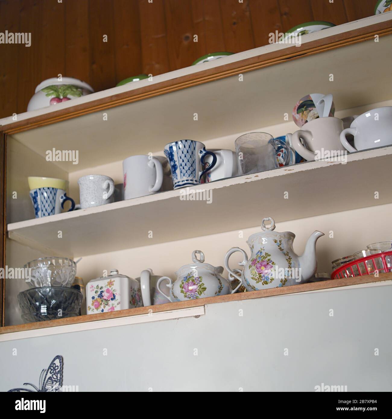 A cupboard with collection of kitchenware on the shelves, indoor angled ...