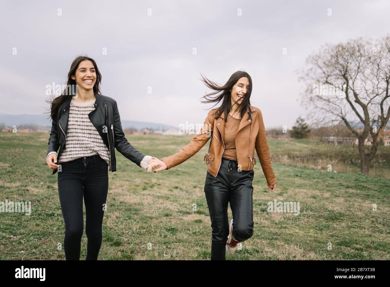 Twin sisters holding hands and laughing outdoors Stock Photo - Alamy