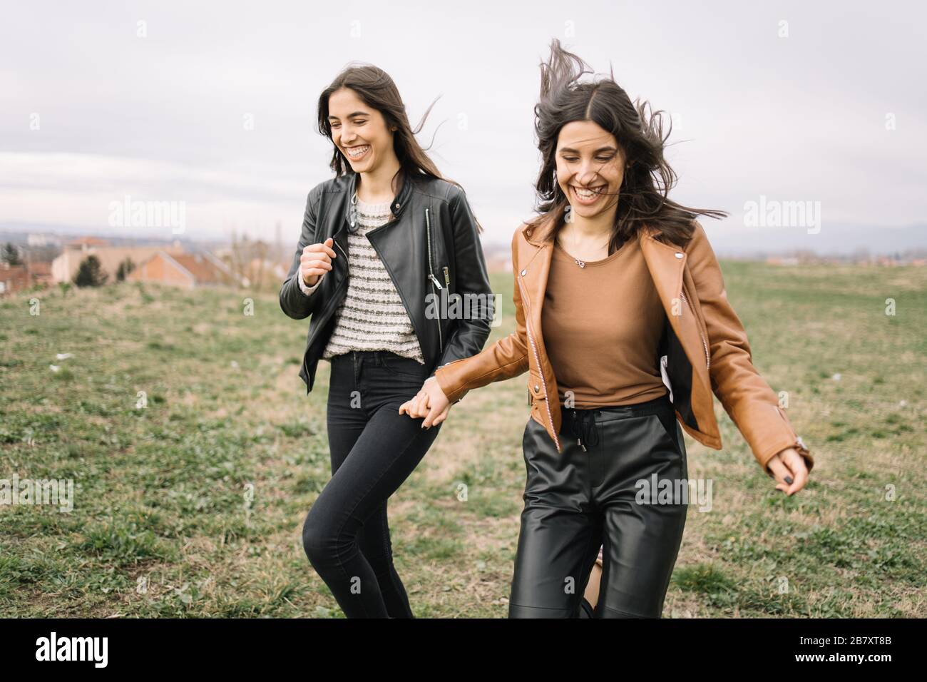 Two girls holding hands and running through a field Stock Photo - Alamy