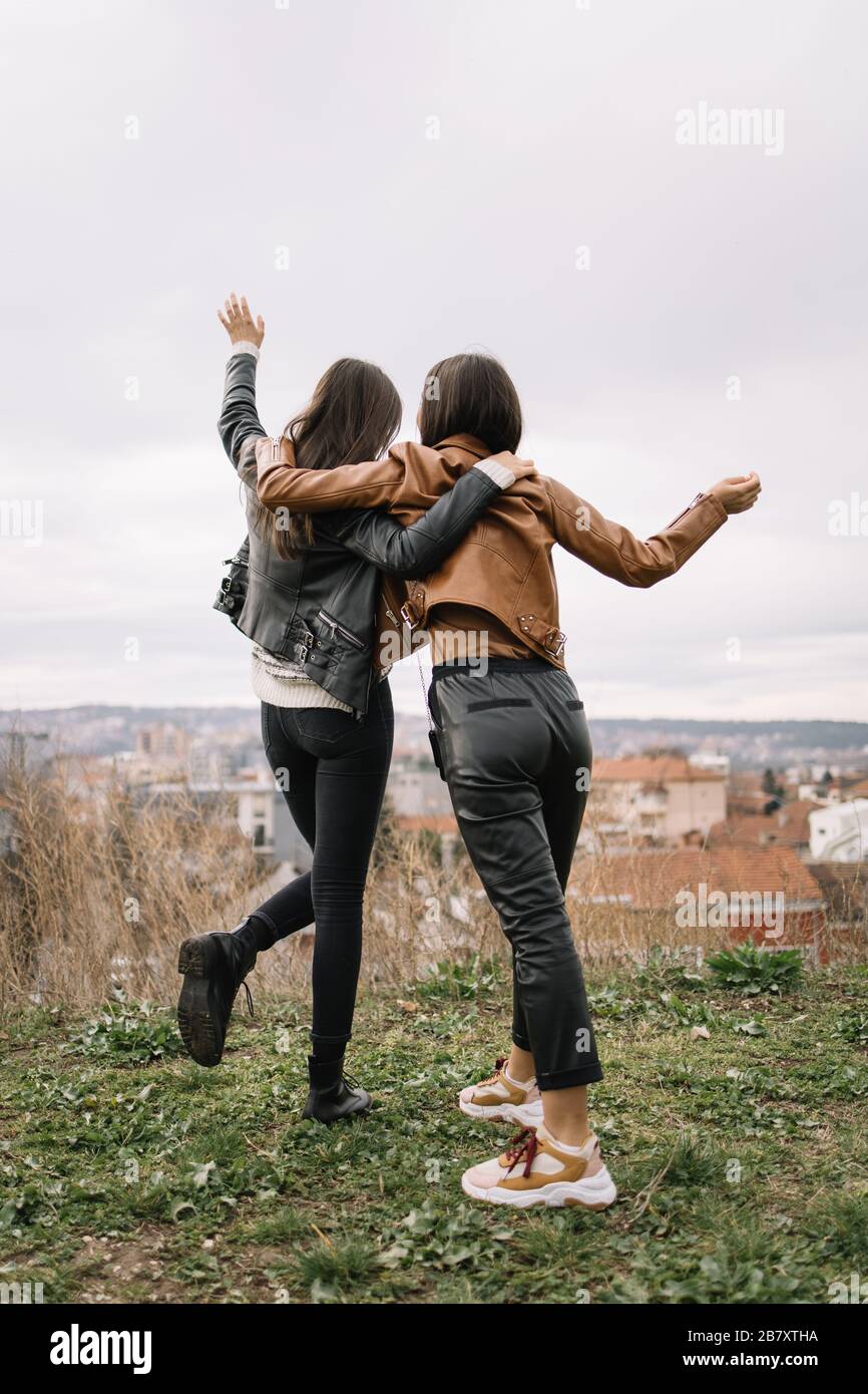Back of girls hugging and waving with hands Stock Photo - Alamy