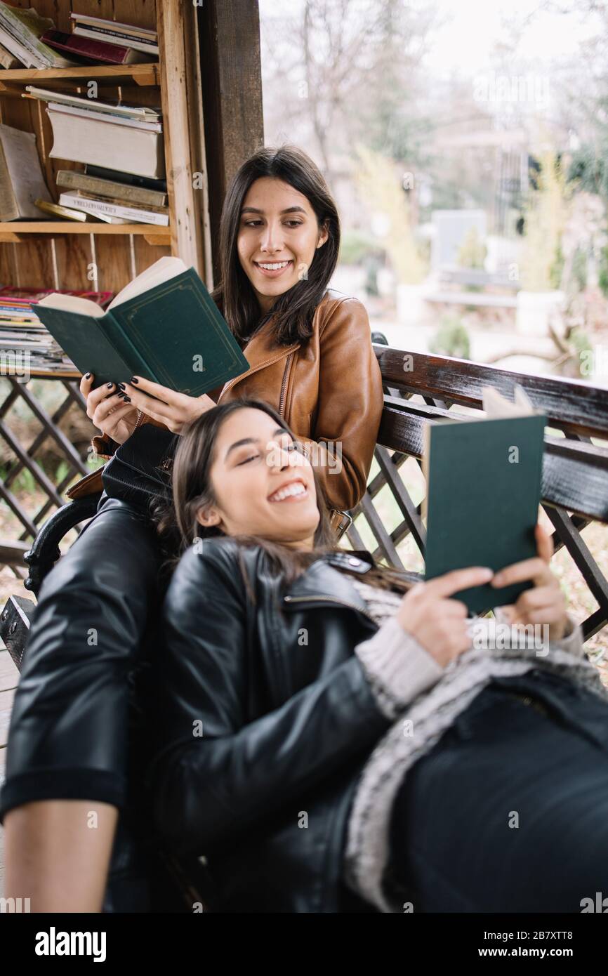 Pretty girls laughing while reading books outdoors Stock Photo - Alamy