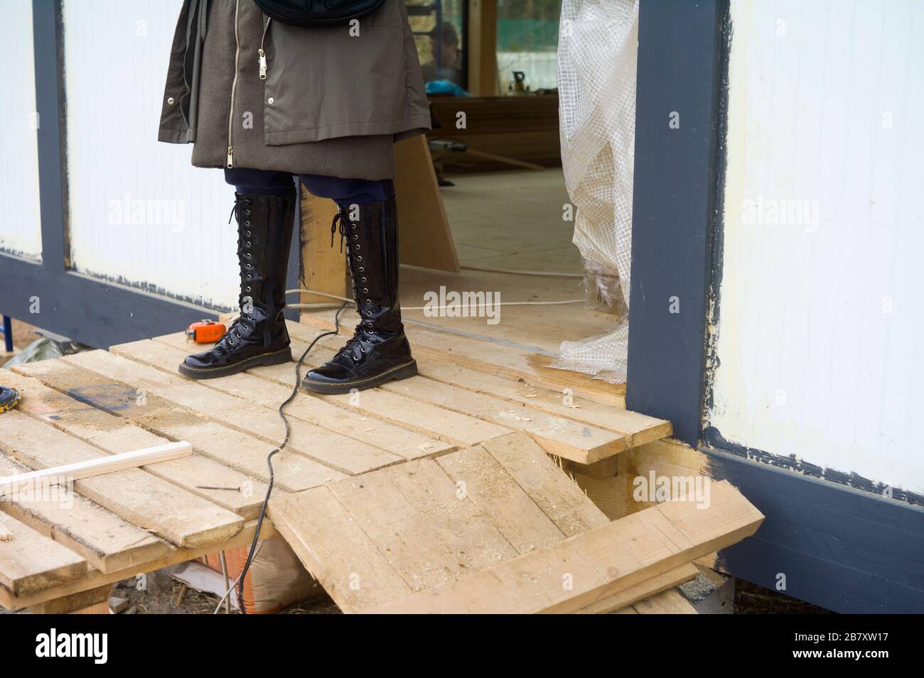A woman standing on the wooden steps of unfinished house Stock Photo ...
