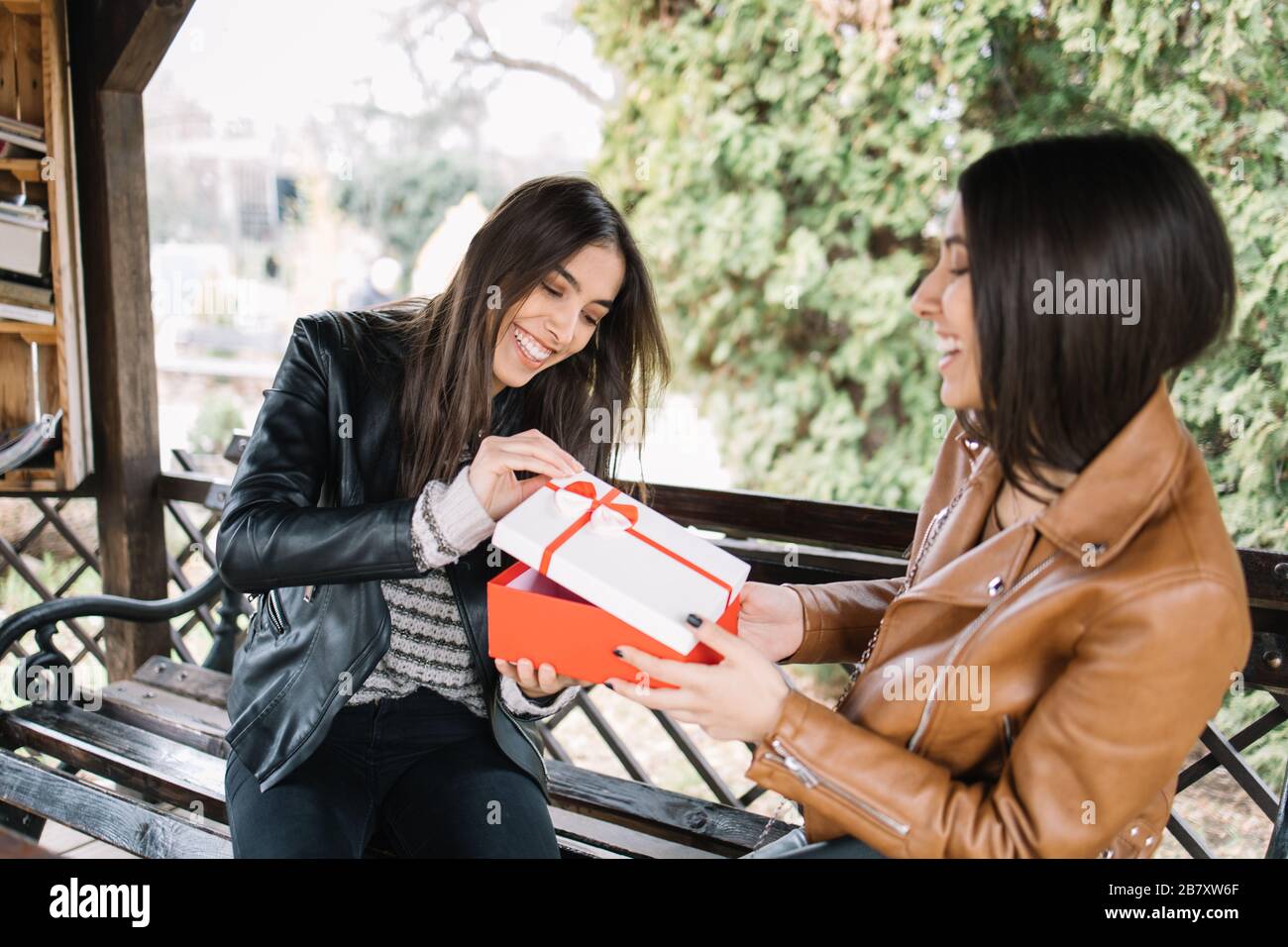 Beautiful girl receiving gift and opening it Stock Photo - Alamy