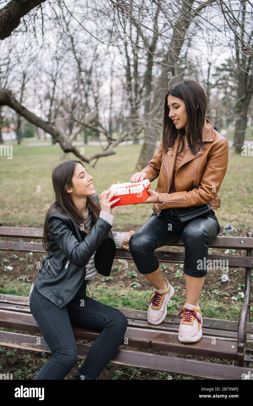Girls sitting on a bench in park with present Stock Photo - Alamy