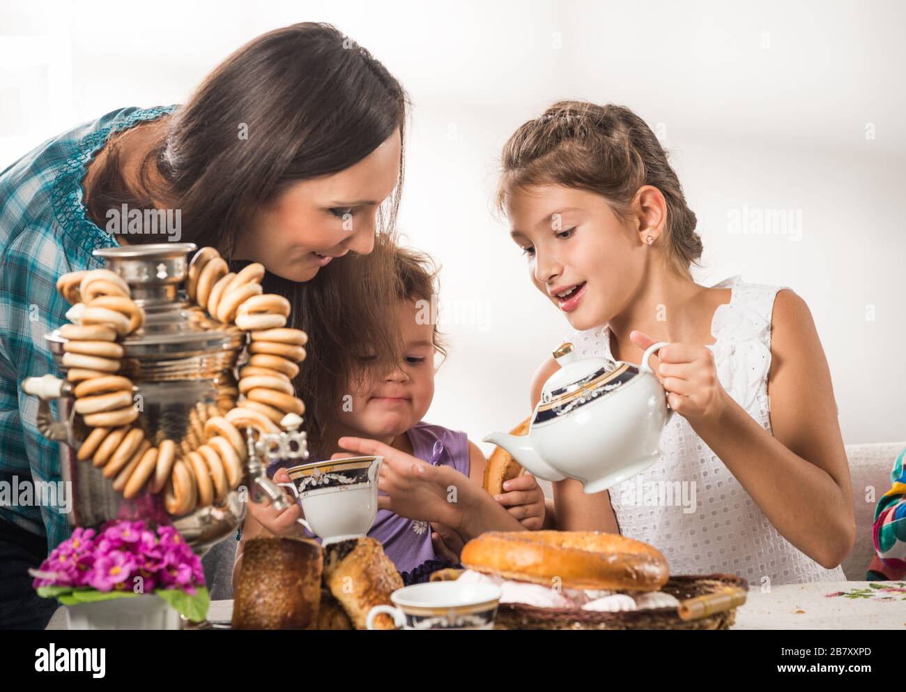 Cute little children drink tea sitting at the table with bagels, bagels ...