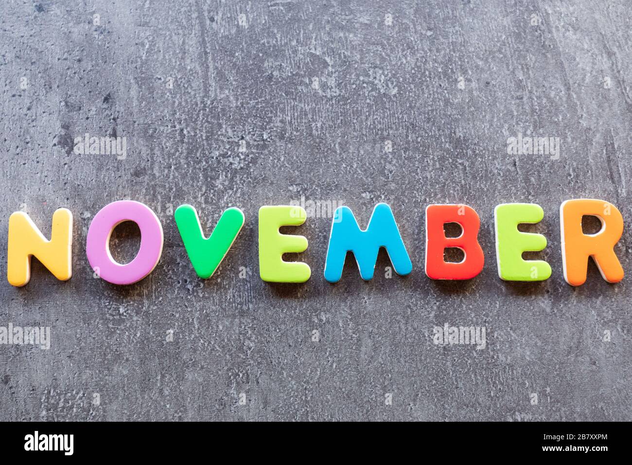 November word written with colorful letters on grey granite stone ...
