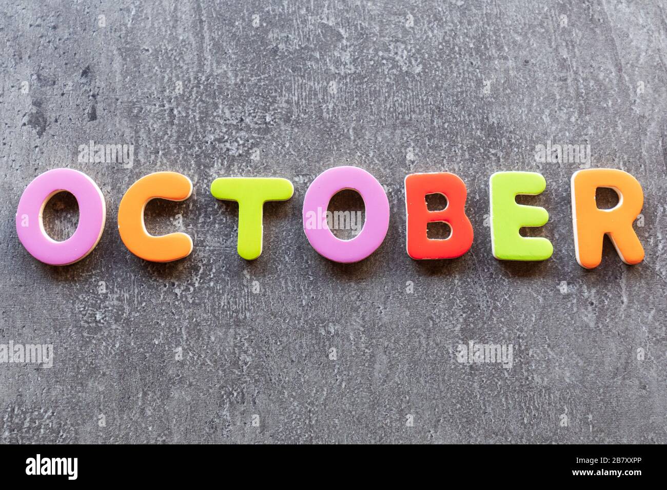 October word written with colorful letters on grey granite stone ...
