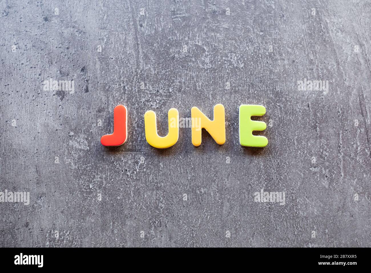 June word written with colorful letters on grey granite stone ...