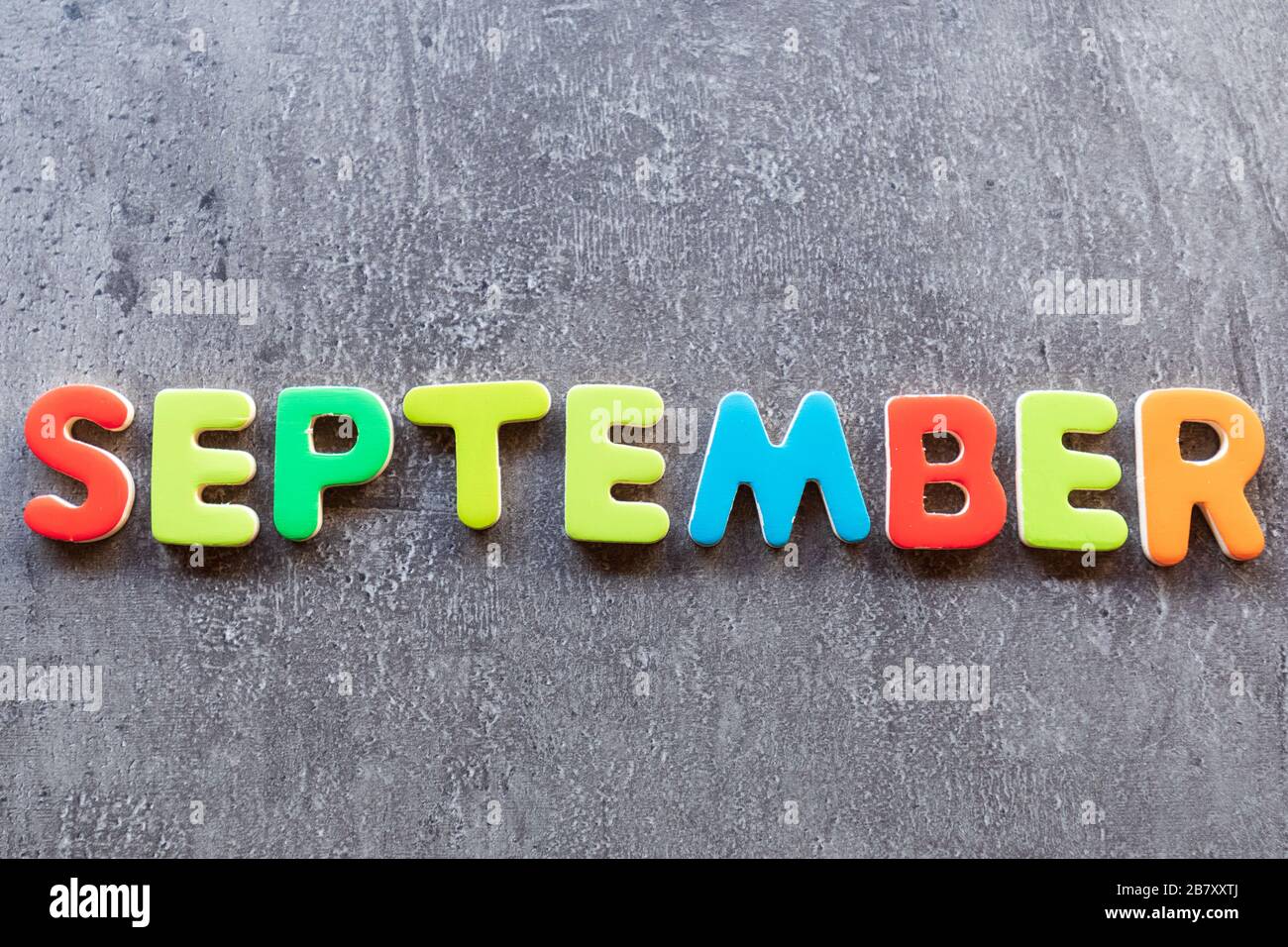 September word written with colorful letters on grey granite stone ...