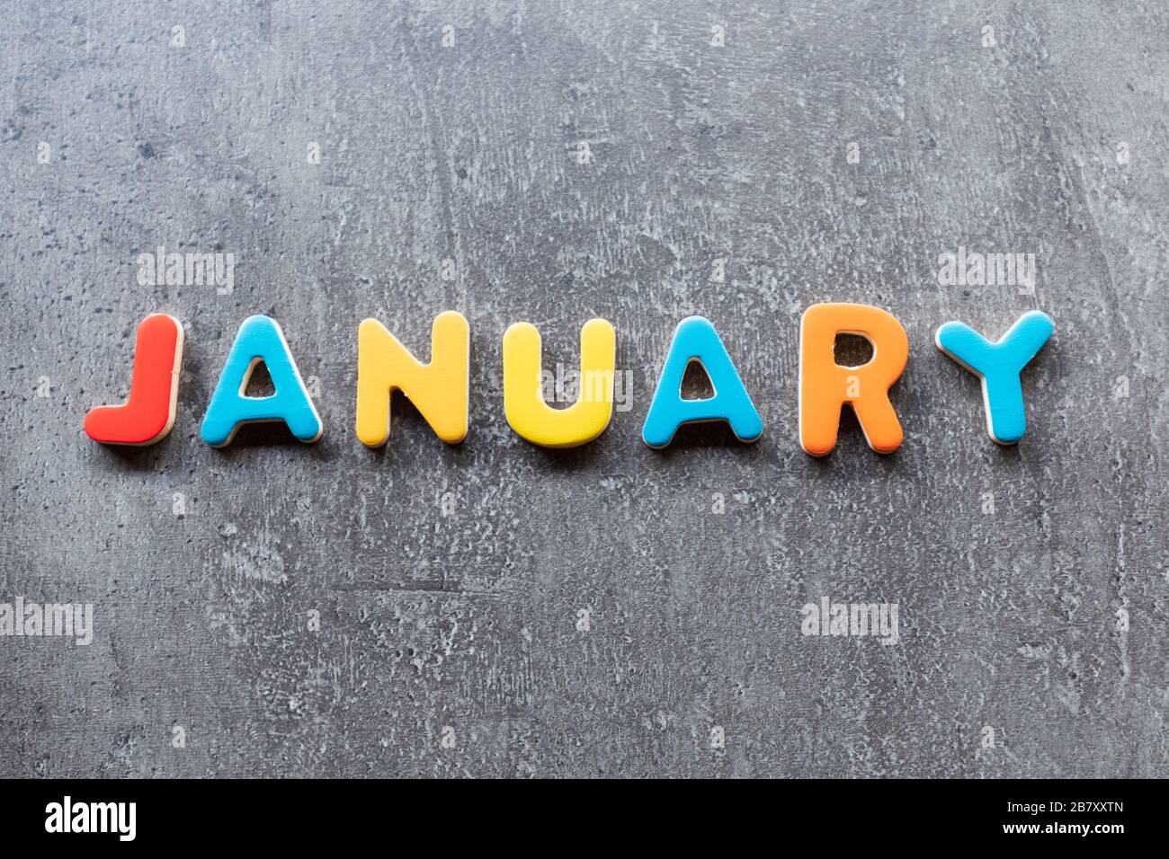 January word written with colorful letters on grey granite stone ...