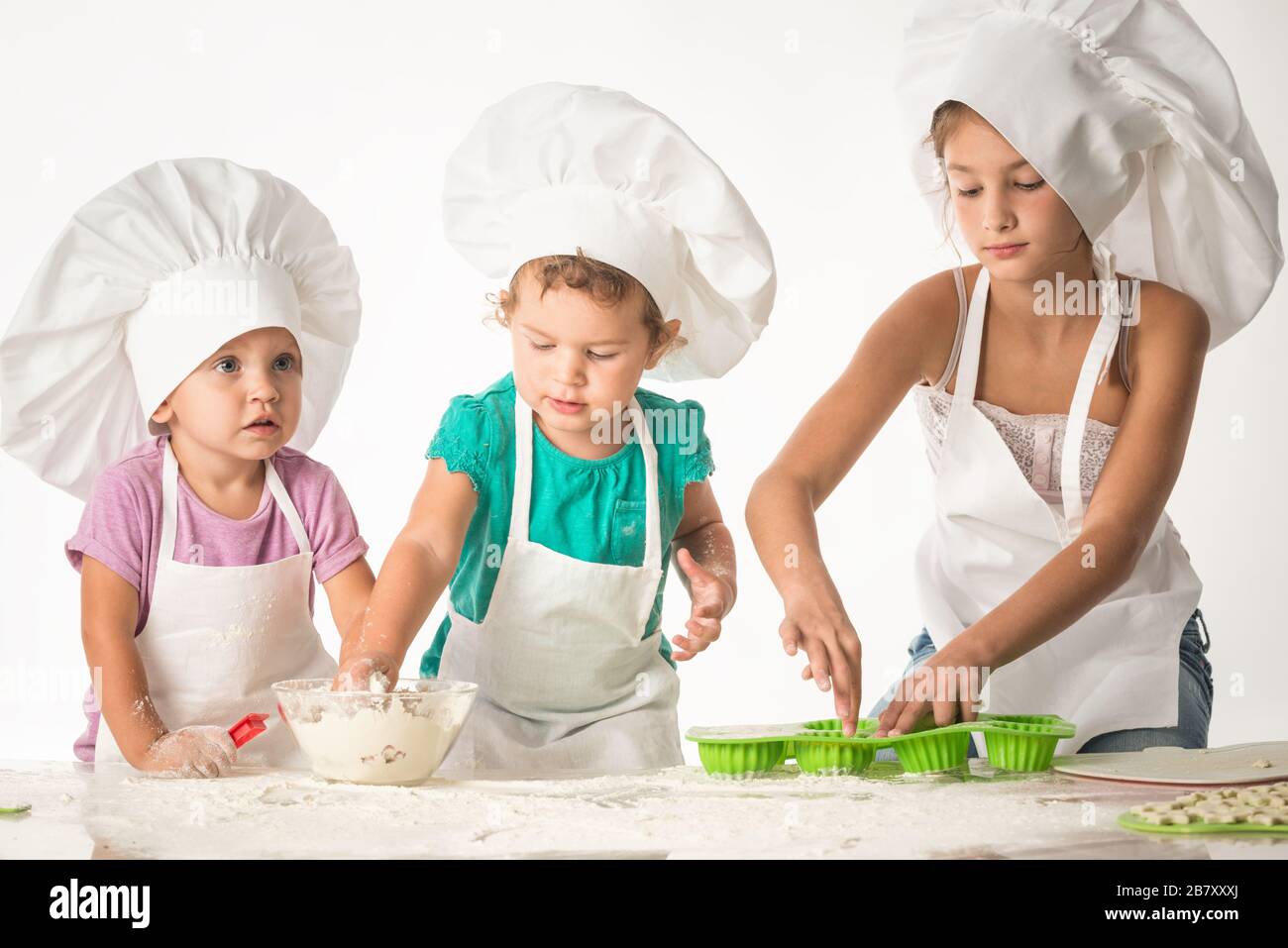 Cute little children in a cook suit cook cookies in the kitchen on a ...