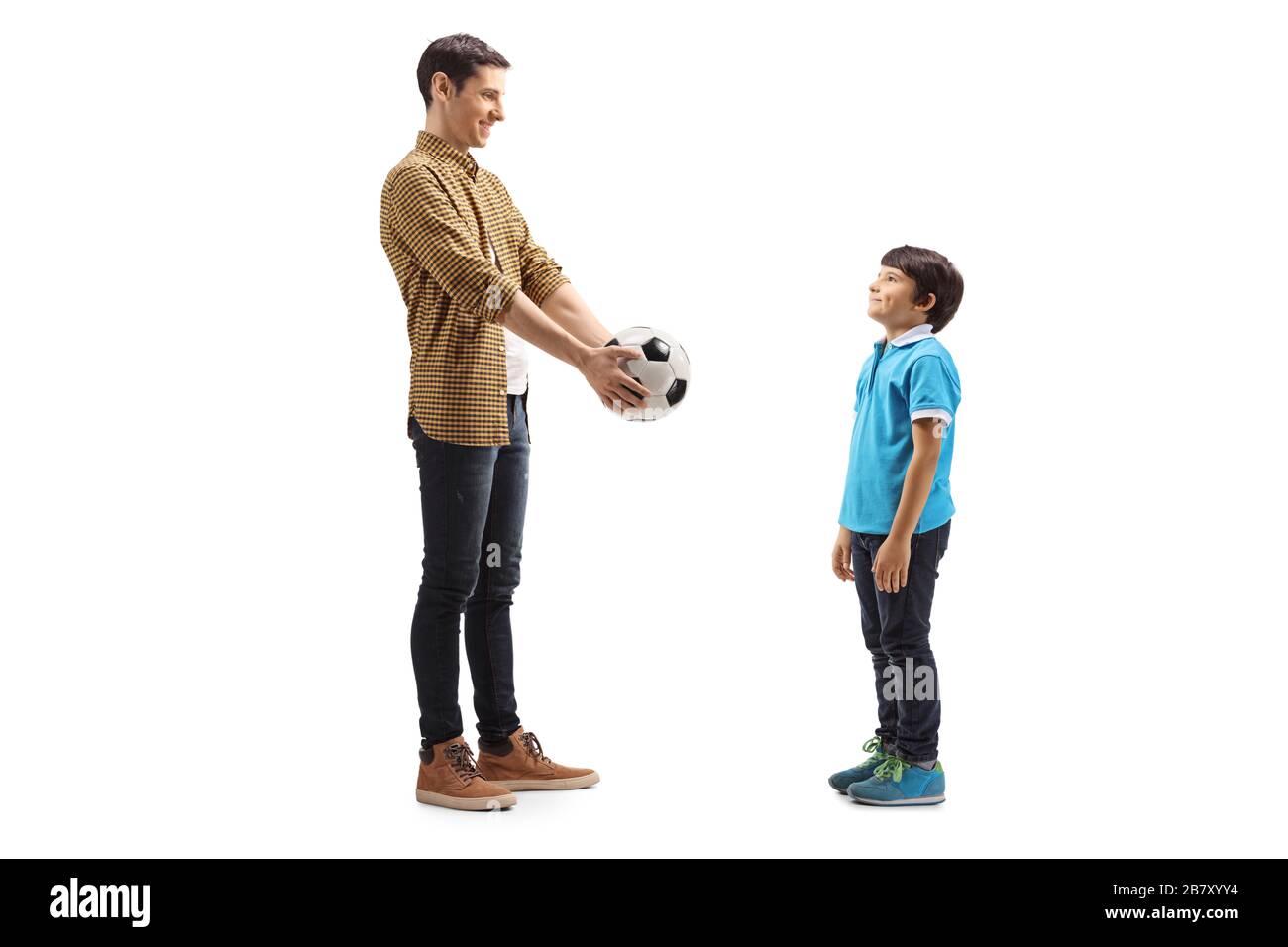 Full length shot of a young man giving a soccer ball to a boy isolated ...