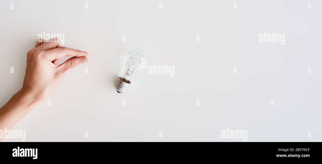 Female hand and a light bulb near it. Isolated on white background ...