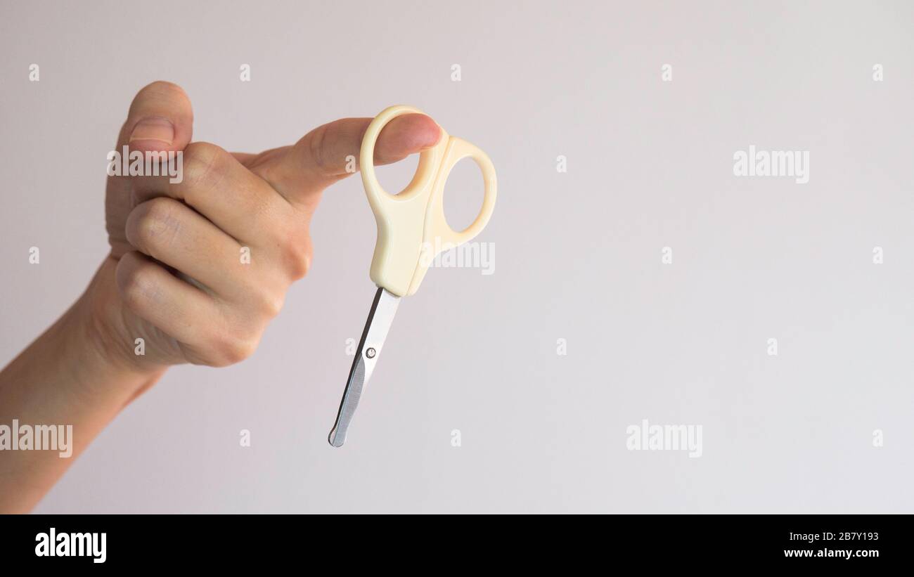 Baby scissors hanging from index finger of a woman's left hand on a ...