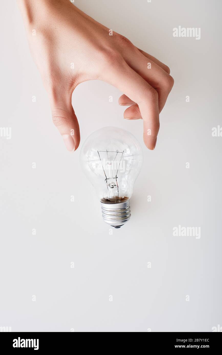 Female hand with a light bulb near it. Isolated on white background ...