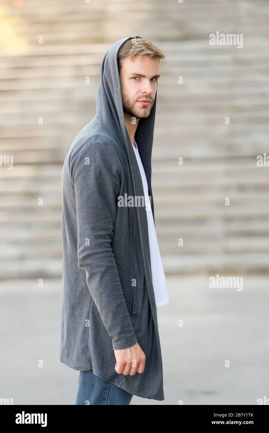 Handsome man with hood standing urban background. Fashion trend ...