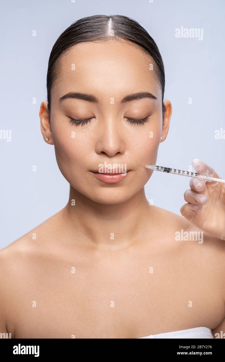 Asian lady having injection while posing in studio Stock Photo - Alamy