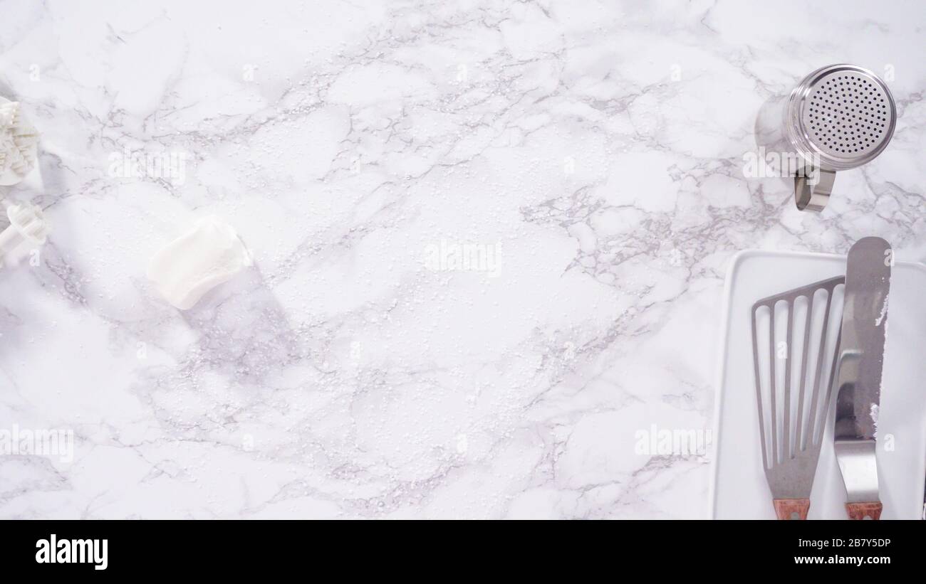 Flat lay. Step by step. Rolling our white fondant on a marble counter ...