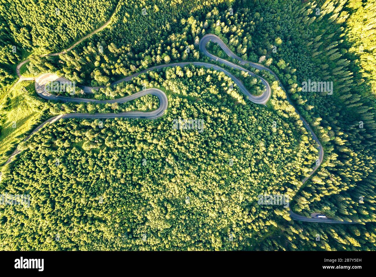 Aerial view of winding road in high mountain pass trough dense green ...