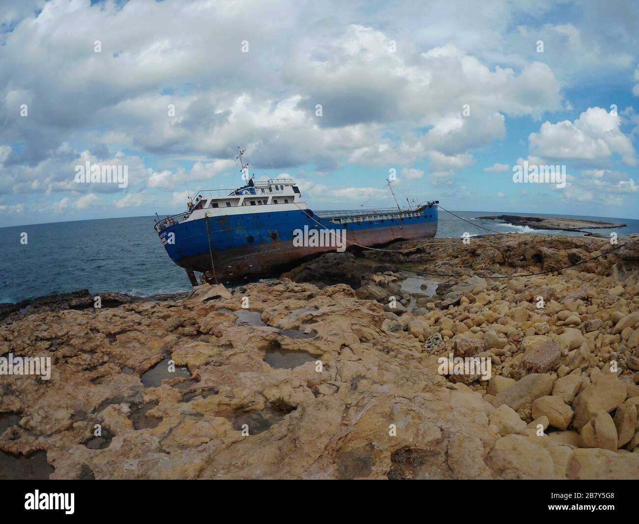 Old abandoned broken ship on the stoned coast sea side. cloudy sky ...