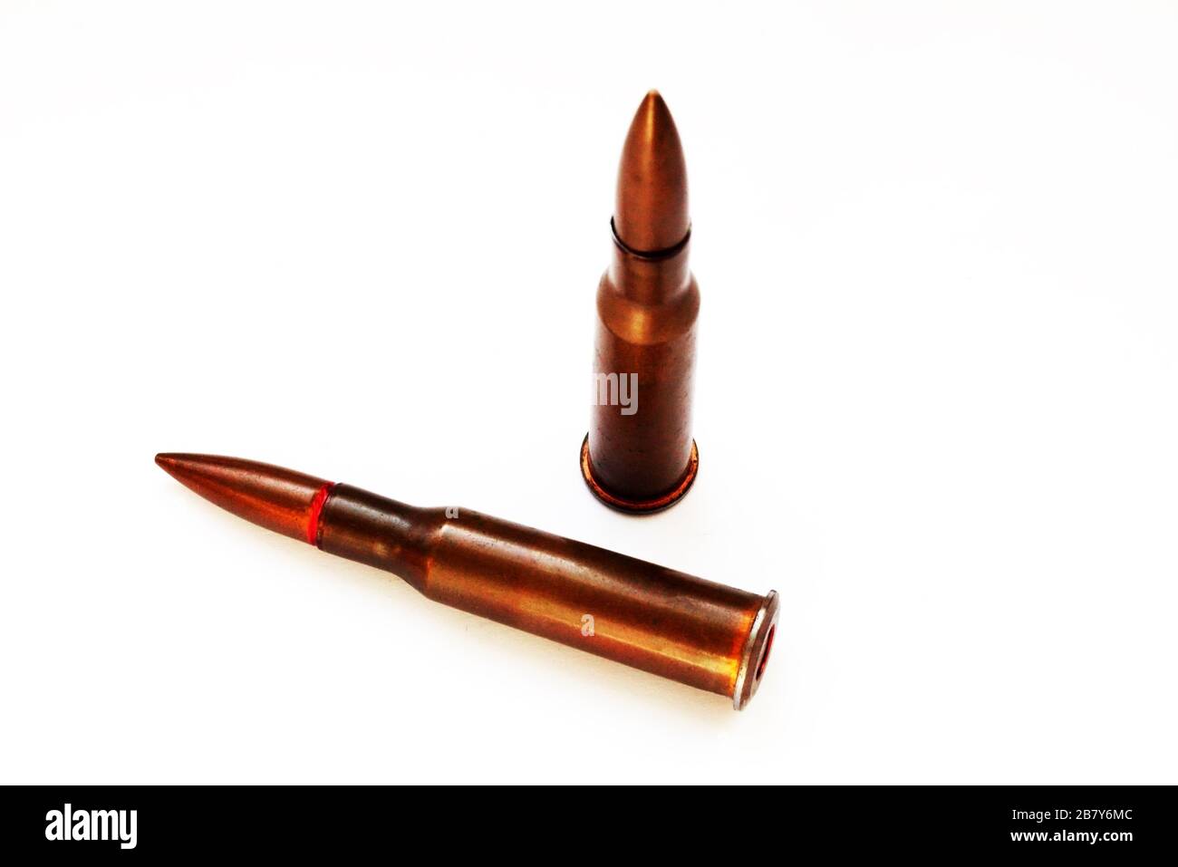 Two cartridges from a large-caliber rifle on a white background close ...