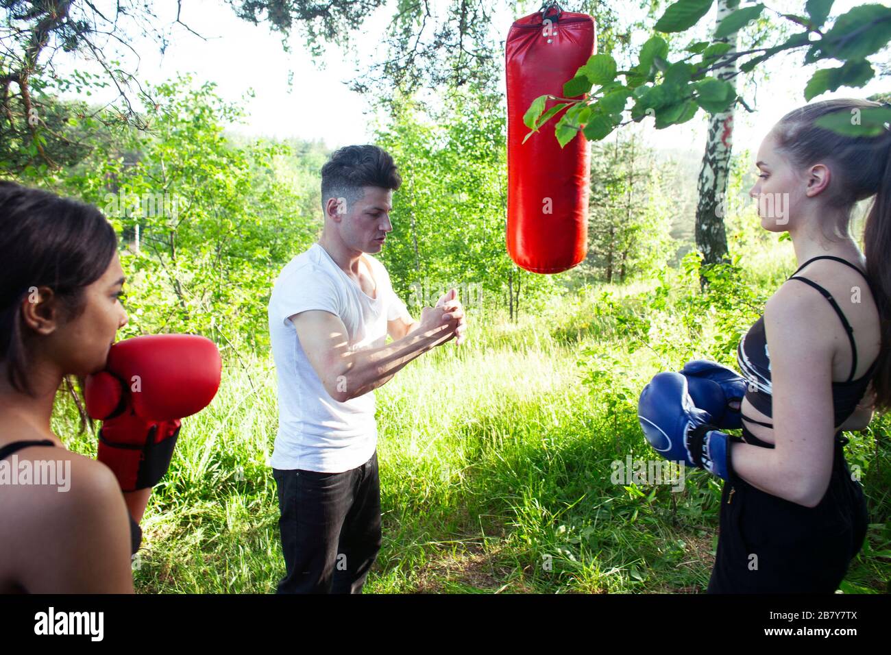 girls fighting boxing outside with coach in green park, sport summer ...