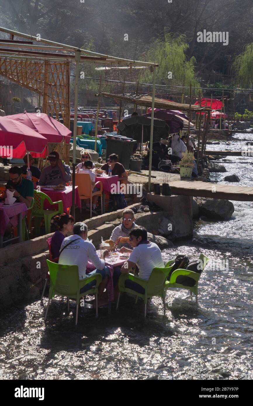 People eating at restaurants by the riverside in a village in the High ...