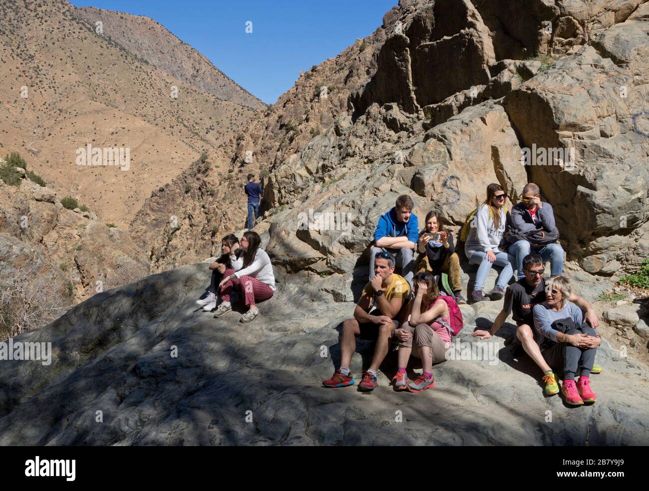 Tourists trekking by a waterfall in the High Atlas mountains in Morocco ...