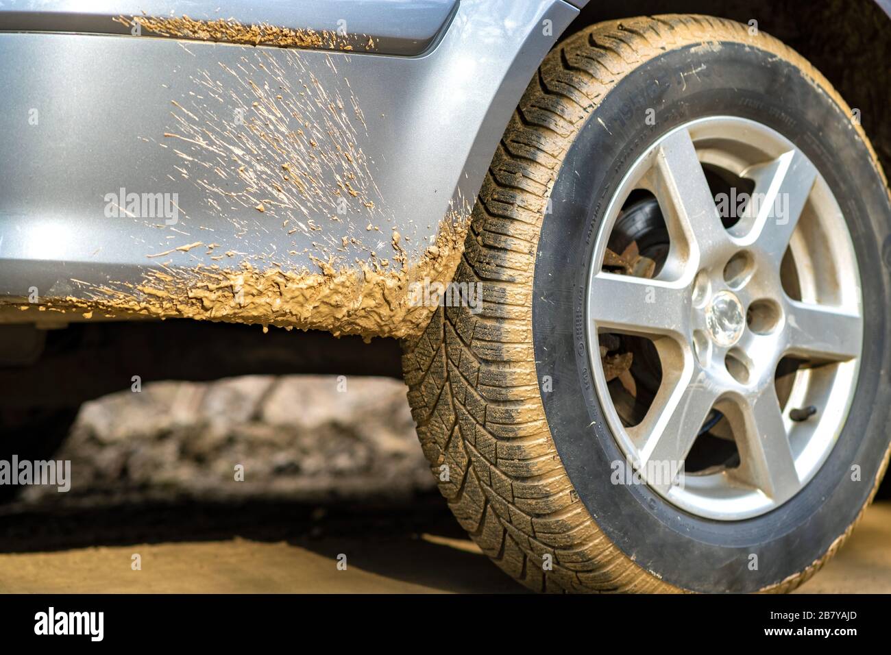 Close up of dirty car wheel with rubber tire covered with yellow mud ...