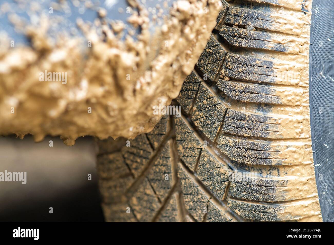 Close up of dirty car wheel with rubber tire covered with yellow mud ...