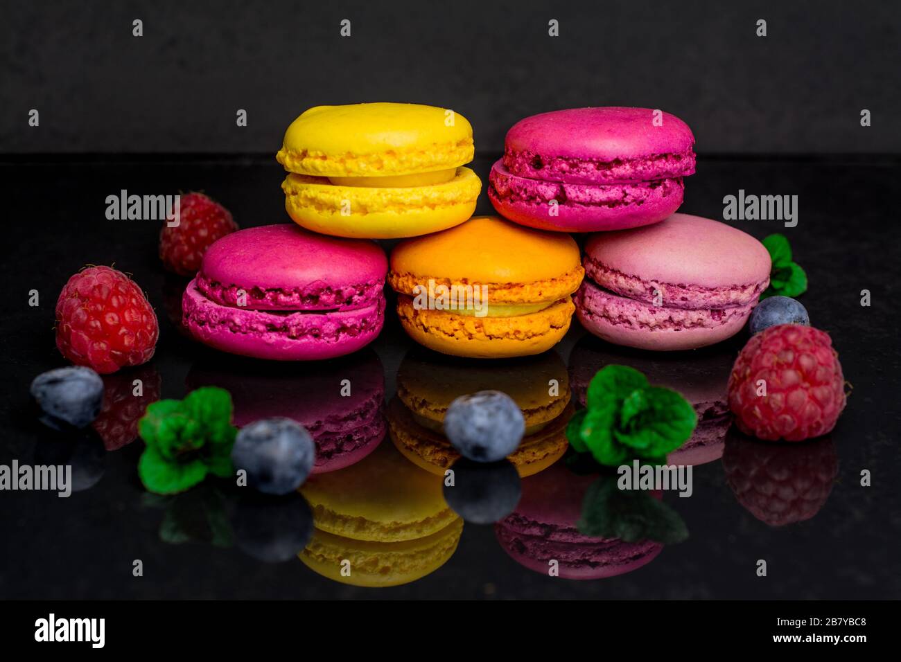 colorful biscuits macaroon raspberry blueberry fresh mint on black ...