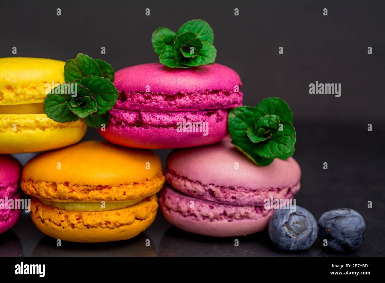colorful biscuits macaroon raspberry blueberry fresh mint on black ...