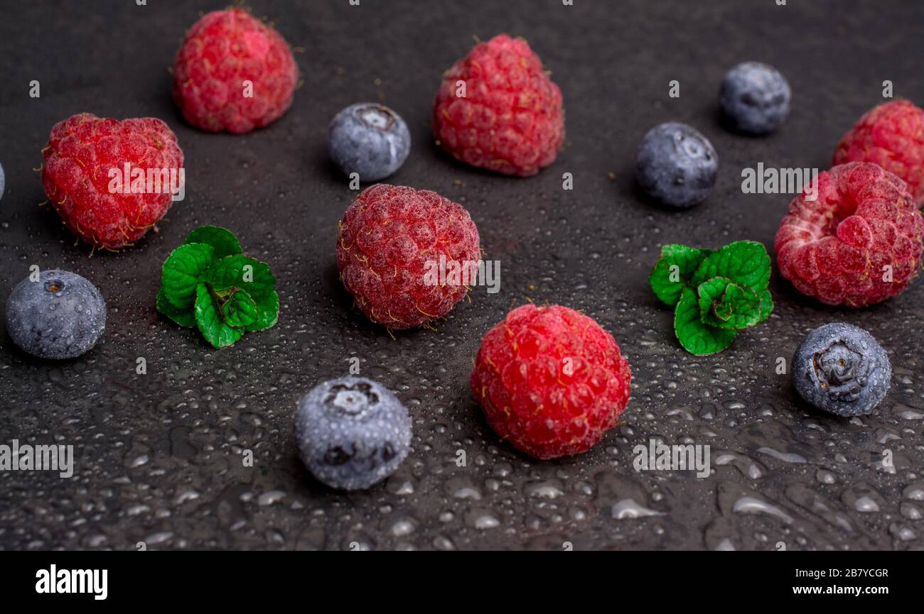 red raspberry blueberry fresh mint on black background with waterdrop ...