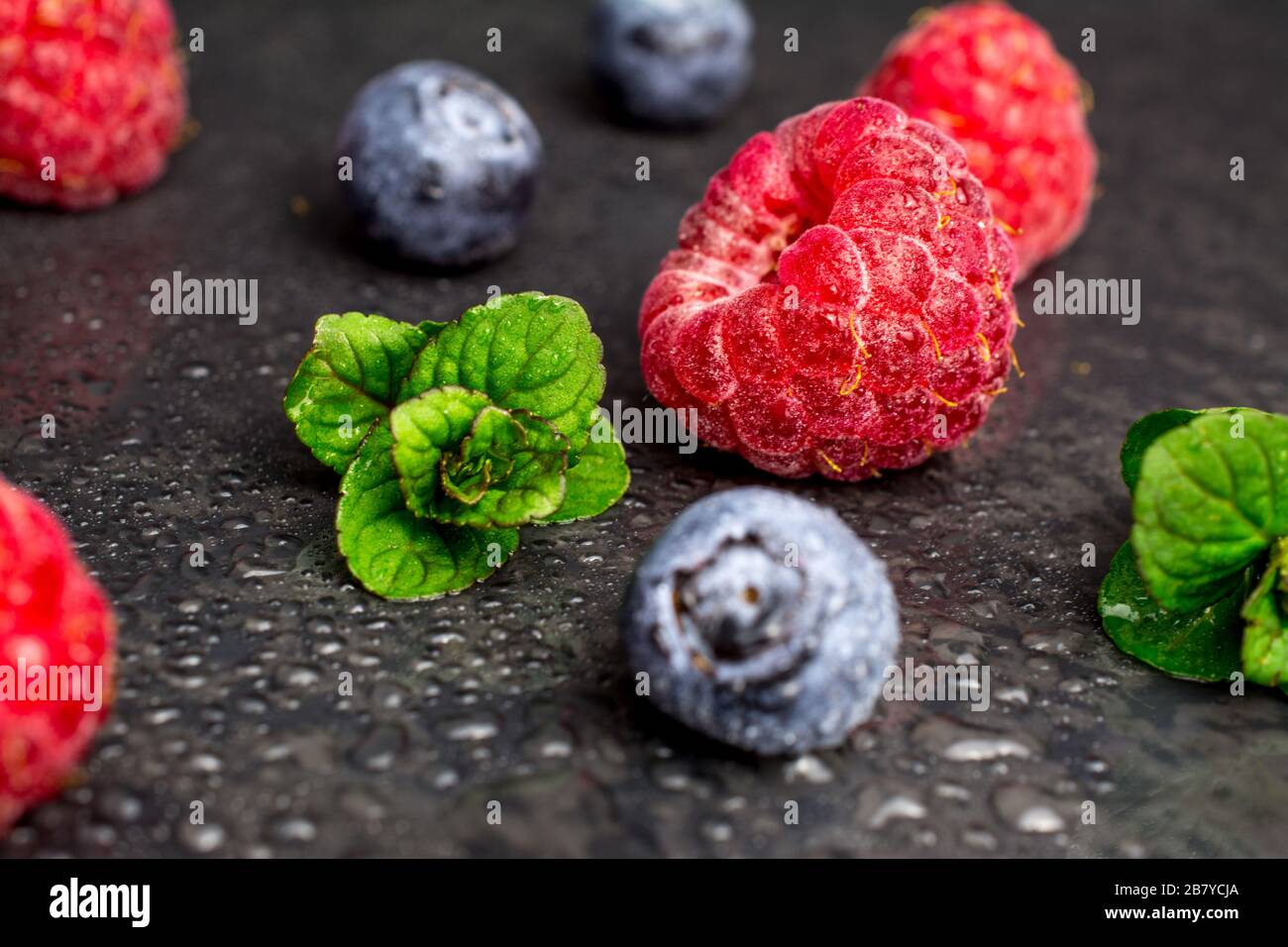 red raspberry blueberry fresh mint on black background with waterdrop ...