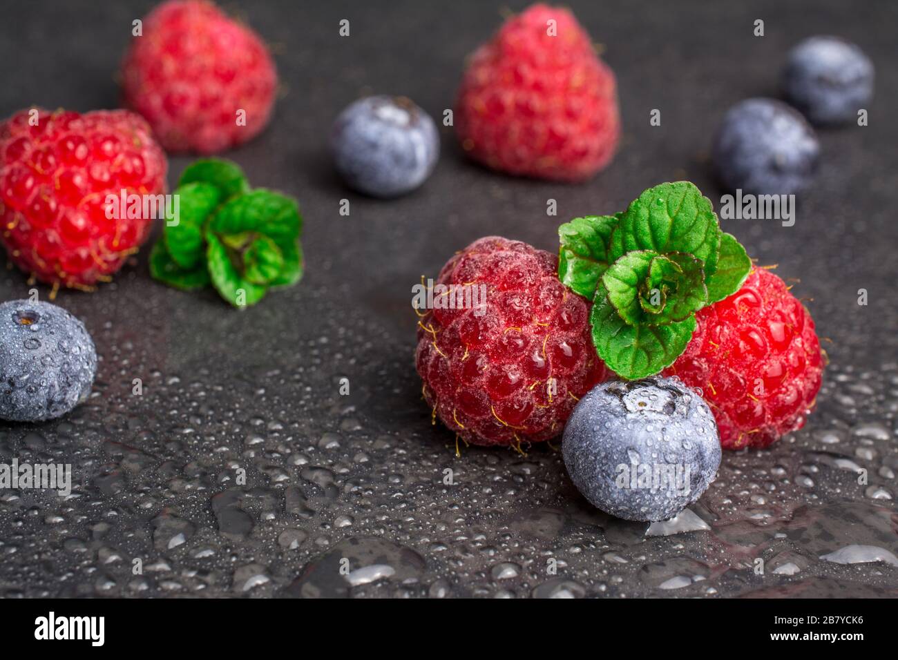 red raspberry blueberry fresh mint on black background with waterdrop ...