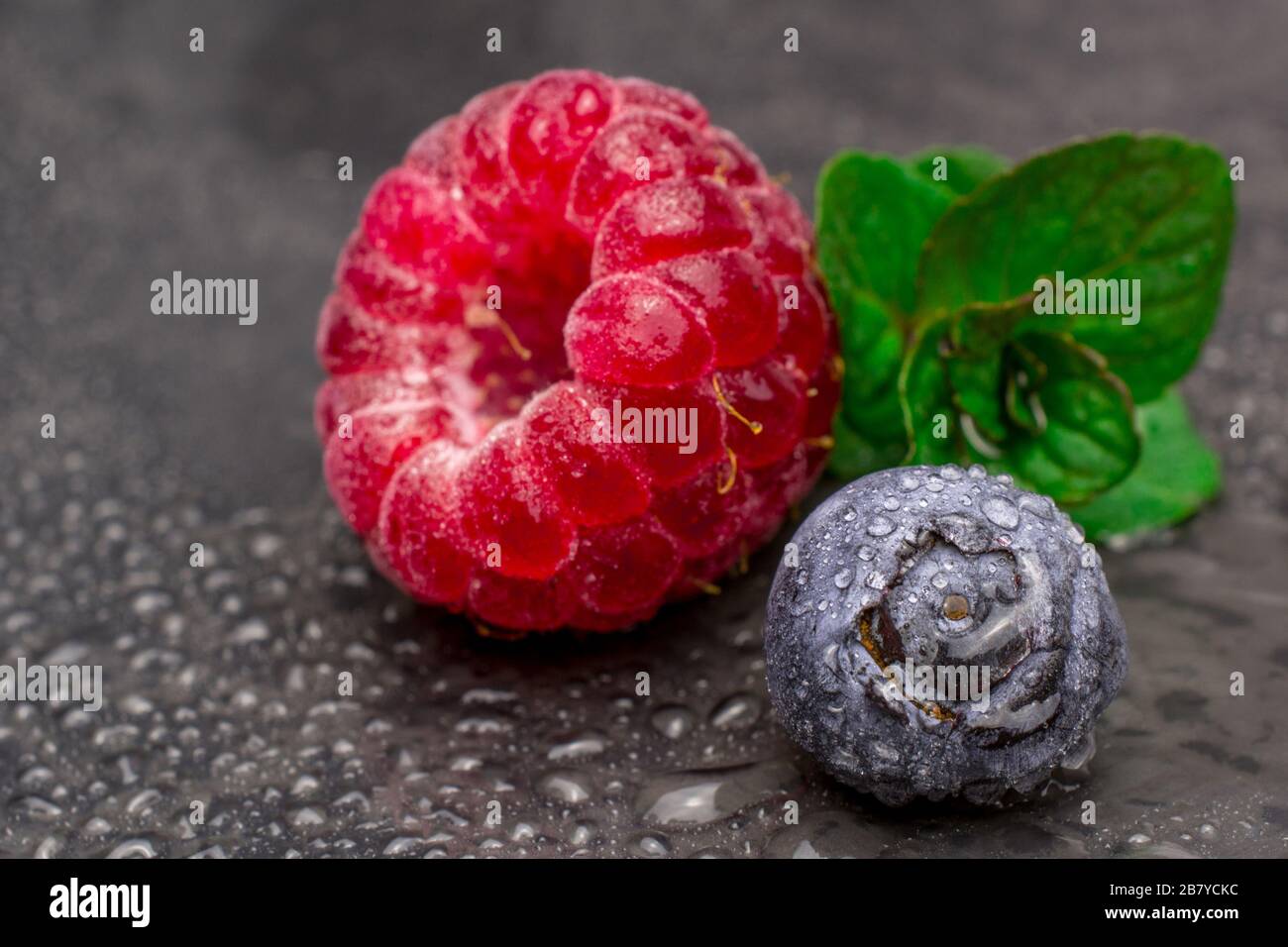red raspberry blueberry fresh mint on black background with waterdrop ...