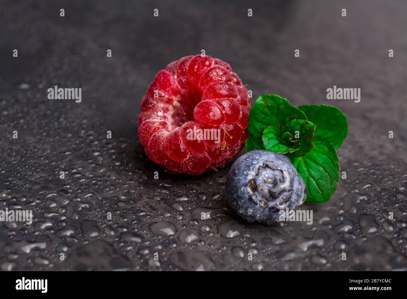 red raspberry blueberry fresh mint on black background with waterdrop ...