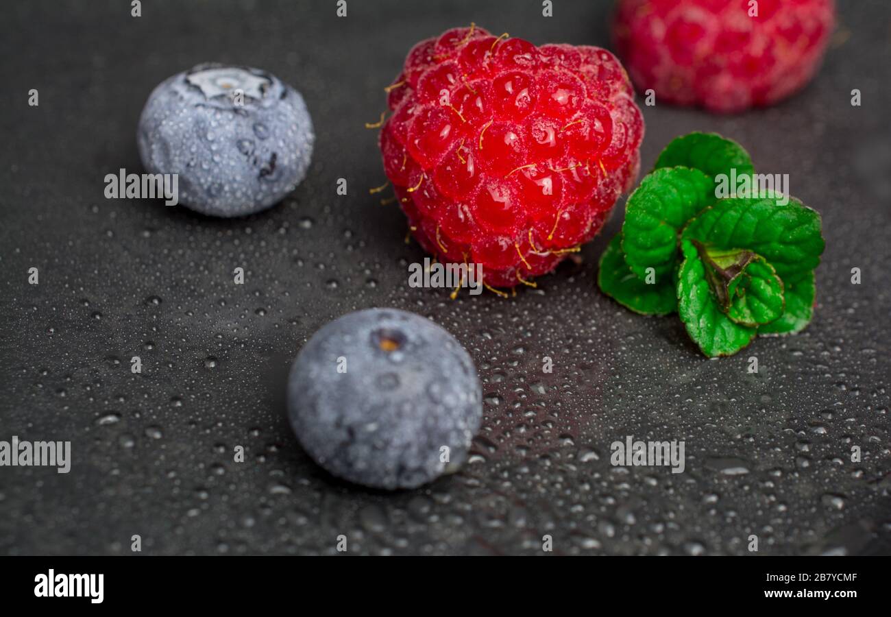red raspberry blueberry fresh mint on black background with waterdrop ...