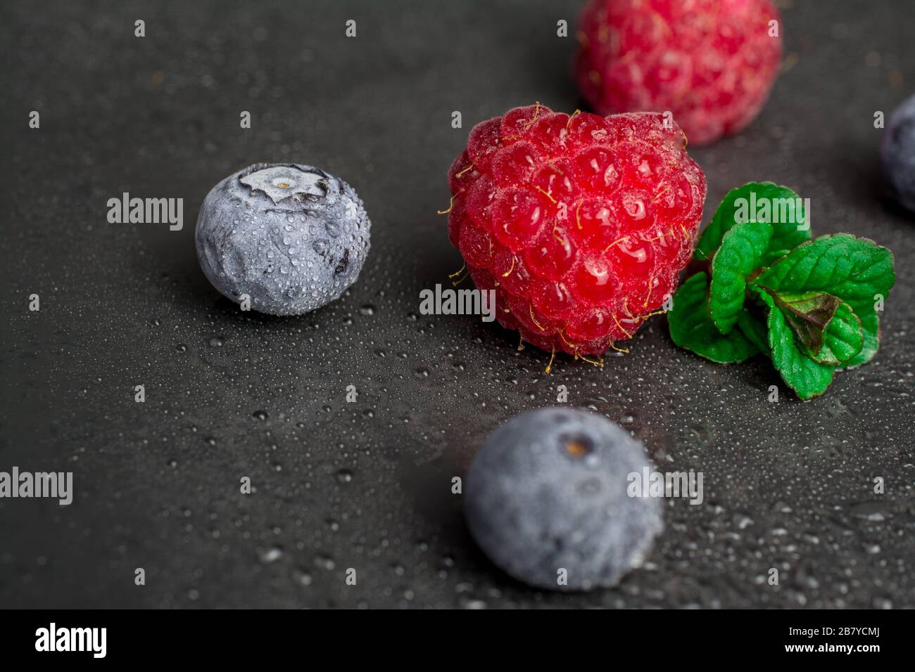 red raspberry blueberry fresh mint on black background with waterdrop ...