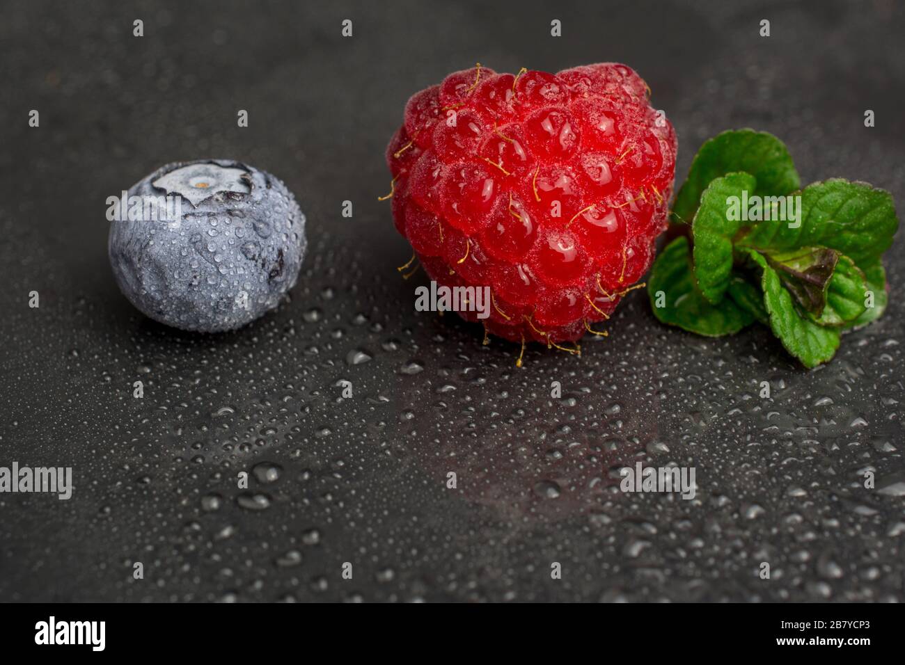 red raspberry blueberry fresh mint on black background with waterdrop ...