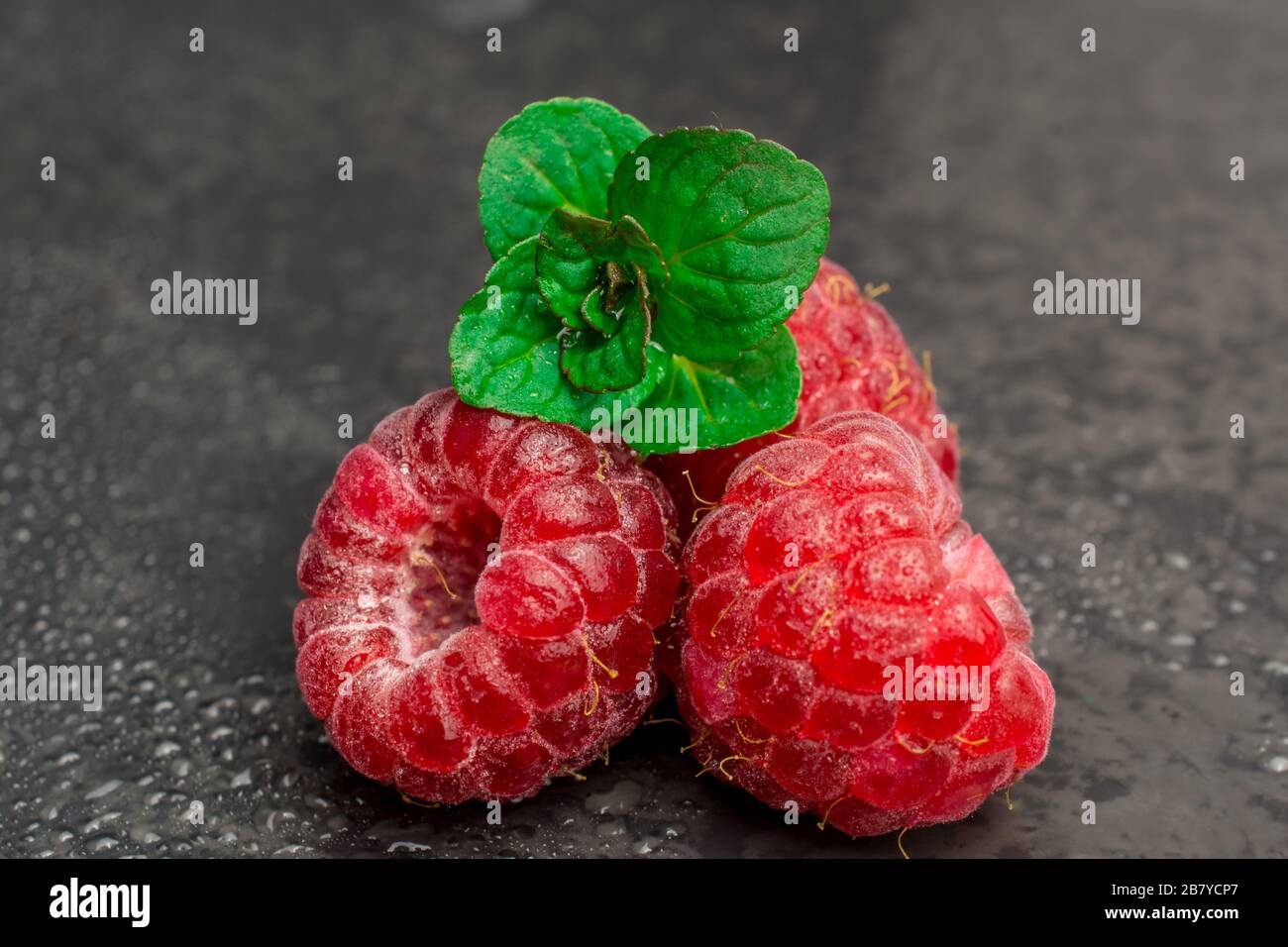 red raspberry blueberry fresh mint on black background with waterdrop ...