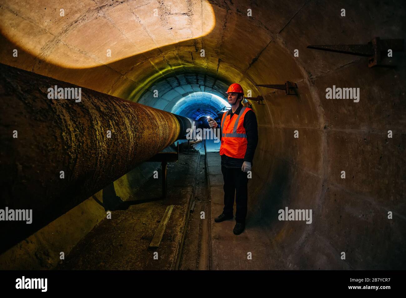 Tunnel worker examines pipeline in underground tunnel Stock Photo - Alamy