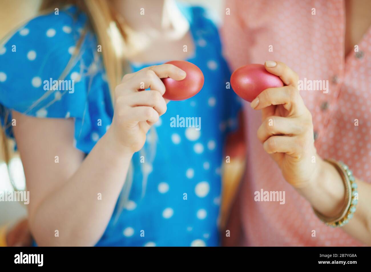Closeup on mother and daughter having egg tapping with red easter eggs ...