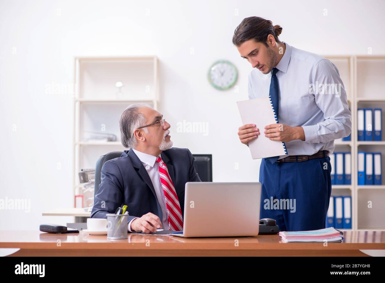 Old boss and young employee in the office Stock Photo - Alamy