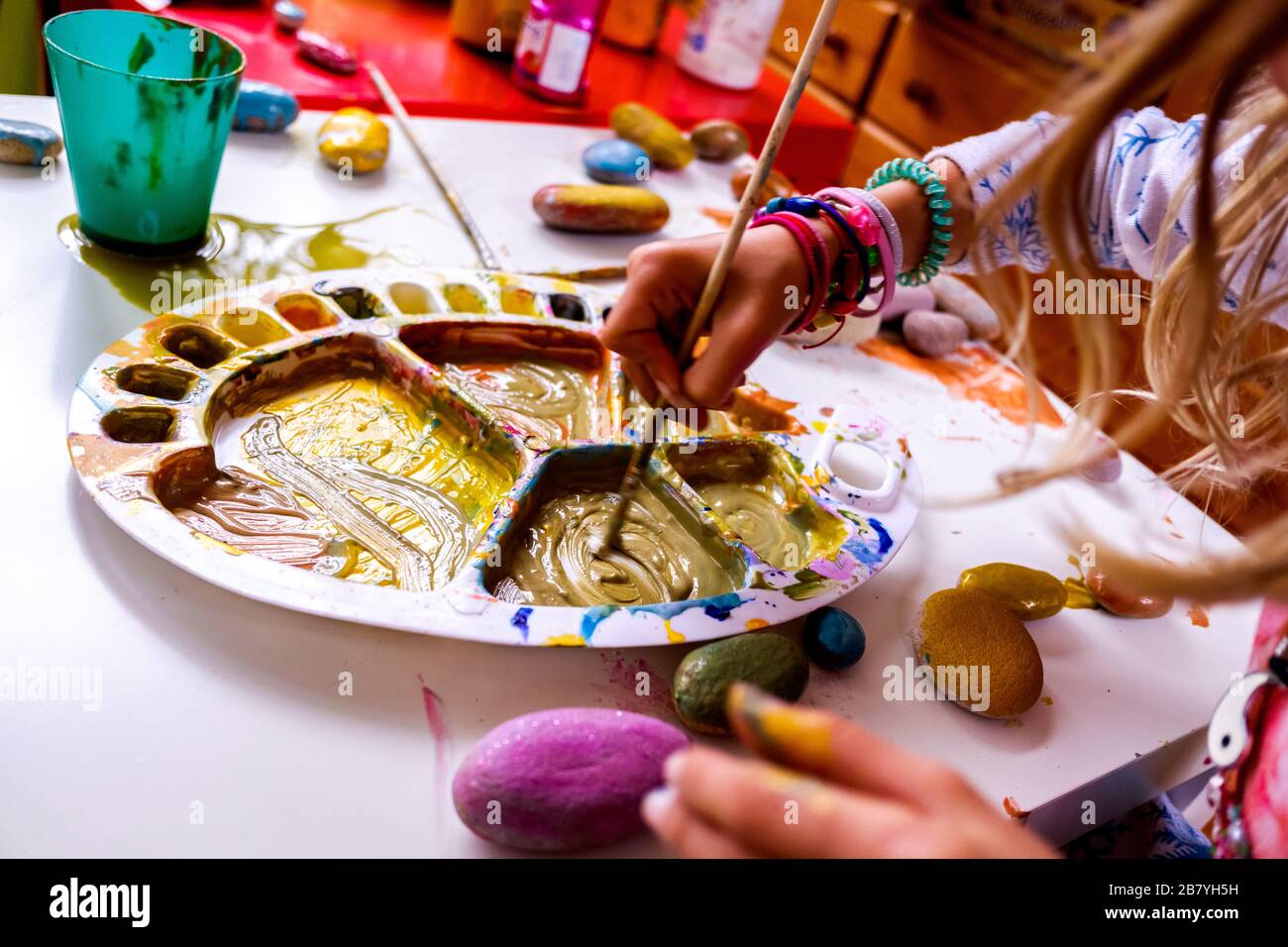 A girl uses an acrylic paint brush to make her drawings on canvas Stock ...