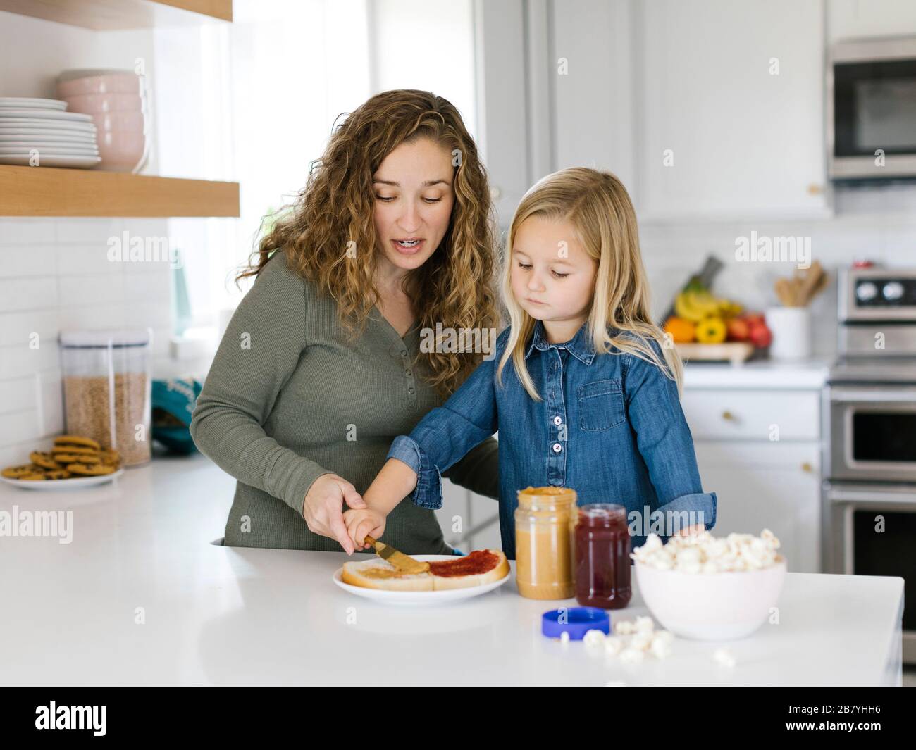Woman making peanut butter and jelly sandwich with her daughter Stock ...