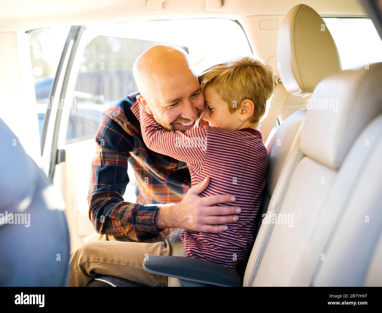Boy sitting in car hugging his father Stock Photo - Alamy